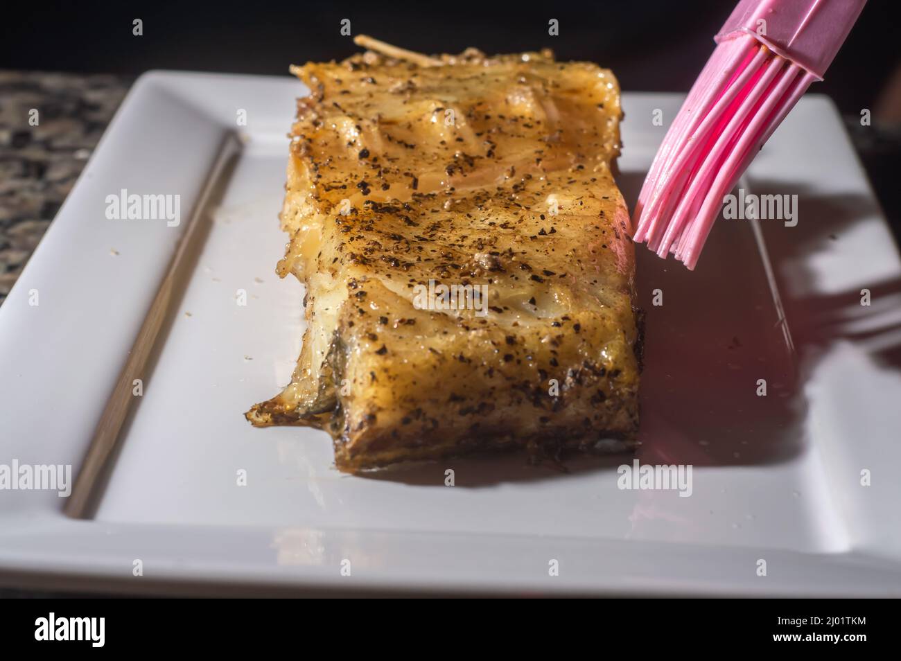 Fish sliced and roasted cod, on a white dish with copy space and dark ...