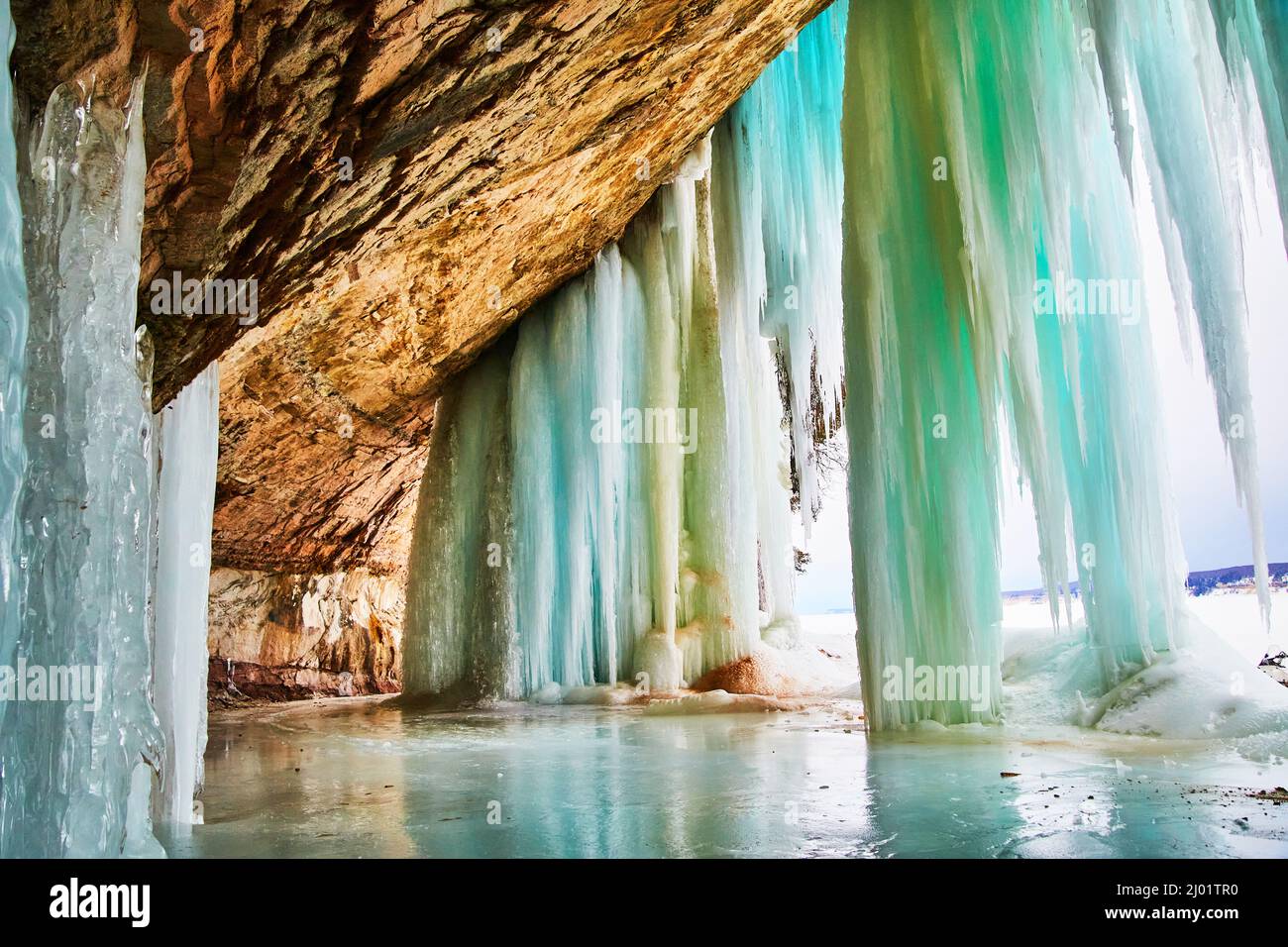 Cave entrance in winter covered in large blue and green icicles Stock ...