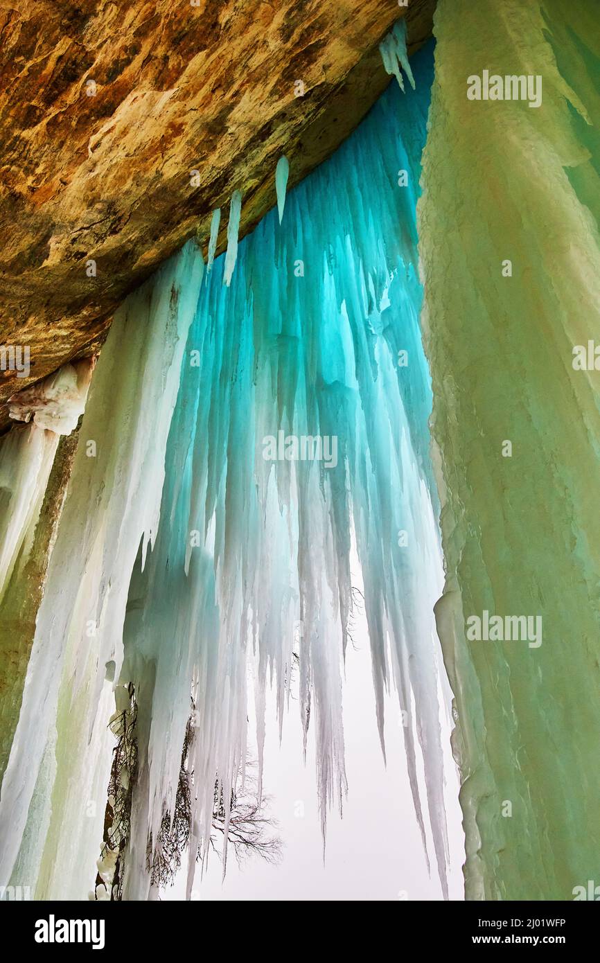 Sharp and dangerous blue icicles dangling off of rocks Stock Photo - Alamy