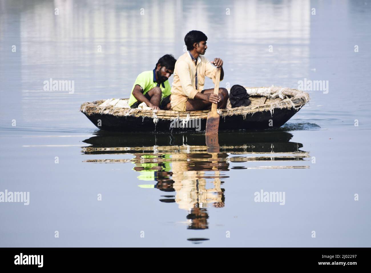 A bot and bot men in river Stock Photo - Alamy