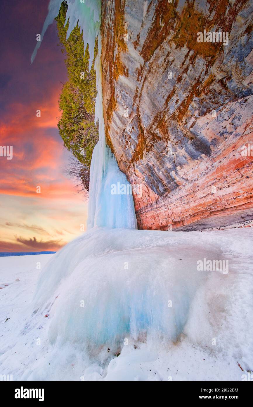 Winter sunrise with colorful rock cliffs covered in ice formations ...