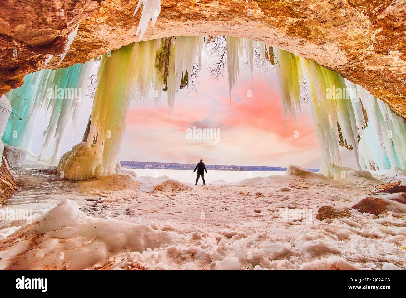Human figure silhouette standing in large ice cave entrance during ...