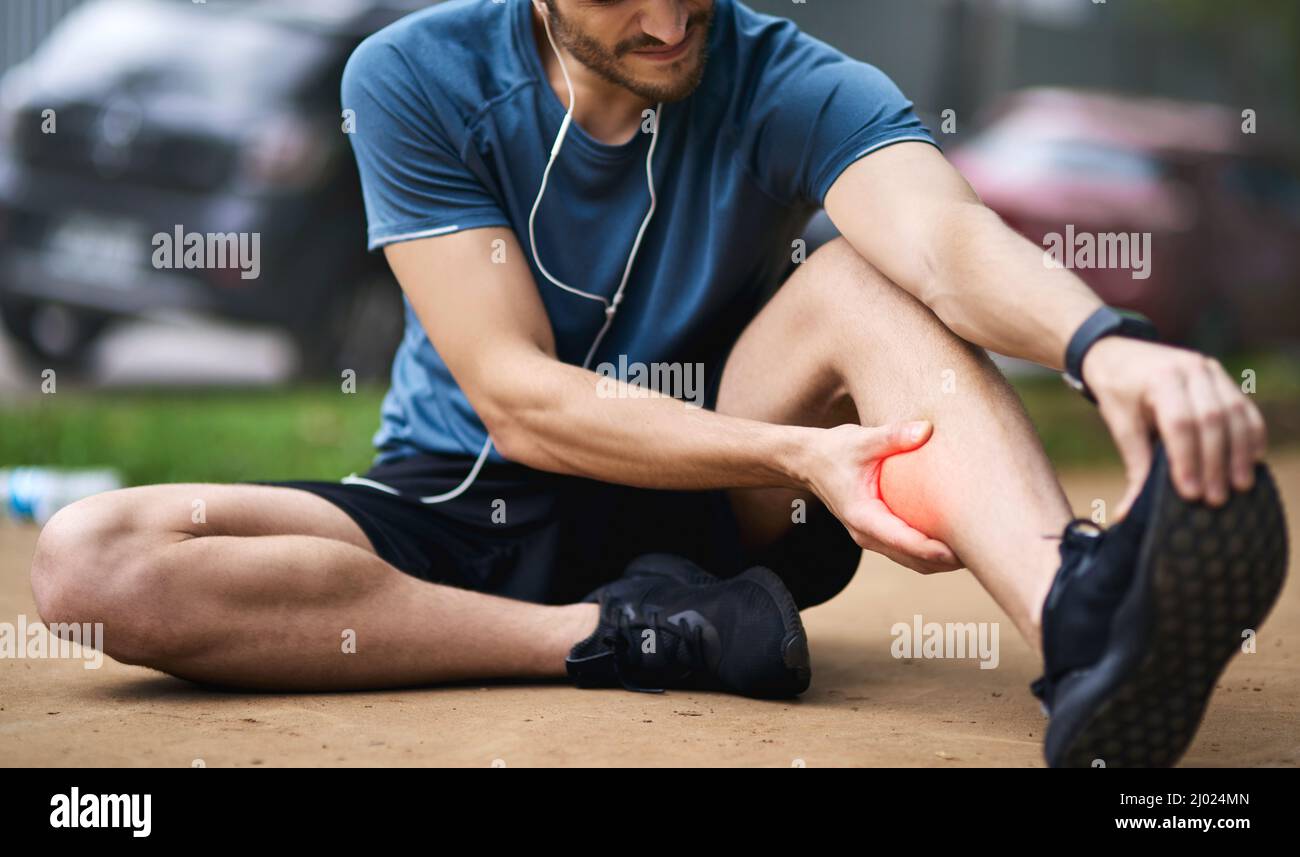 This injury calls for a timeout. Shot of a sporty young man holding his ...