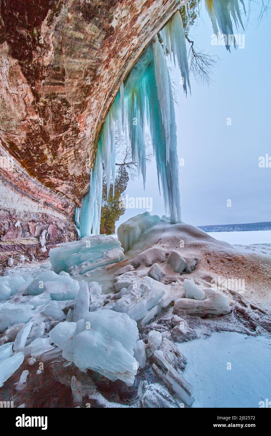 Ice cave opening on rocks and lake with blue icicles Stock Photo - Alamy