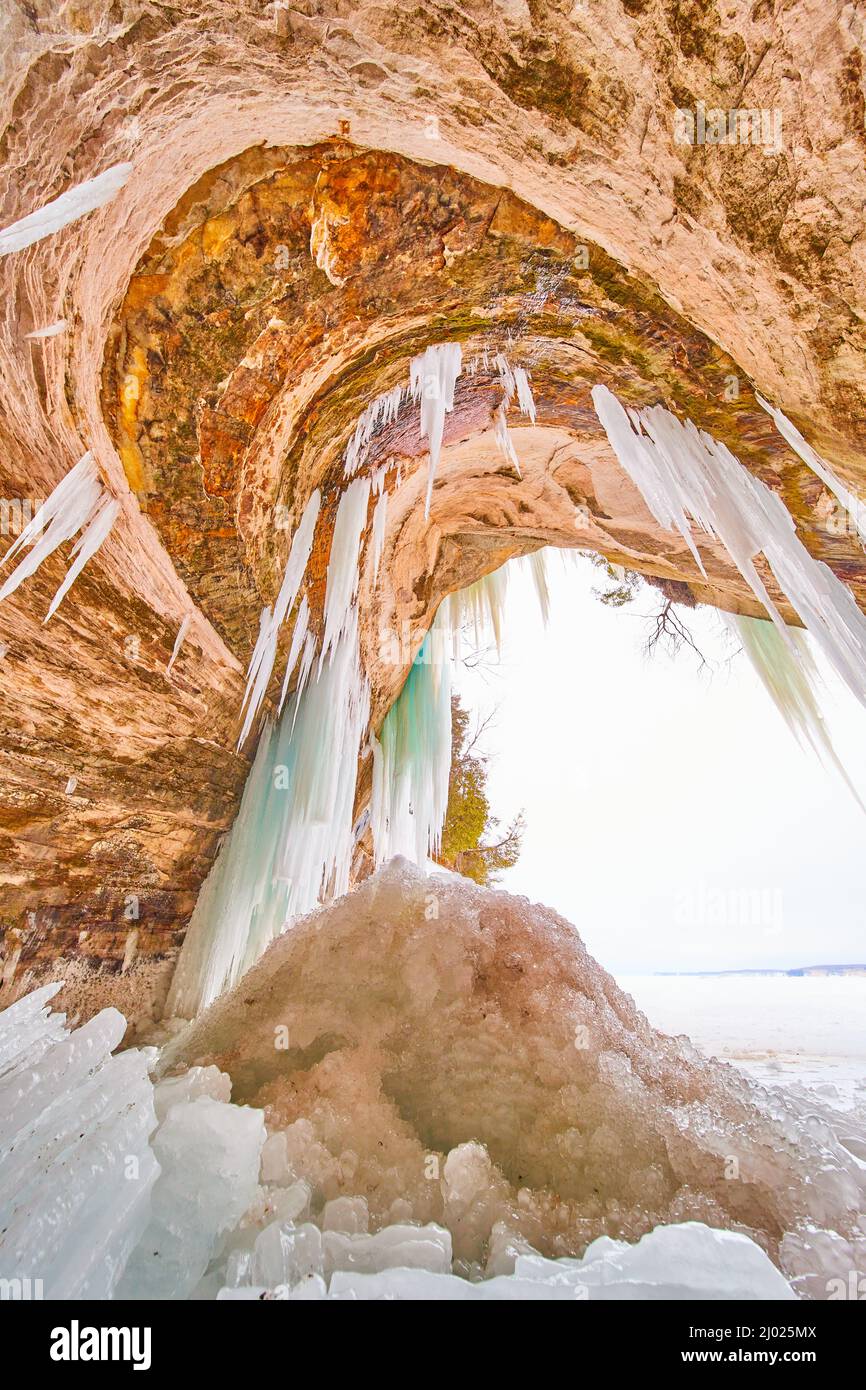 Detail of ice cave entrance with wavy rock formations and frozen ...