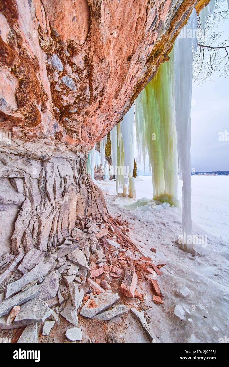 Rock cliffs with large icicles hanging by frozen lake Stock Photo - Alamy