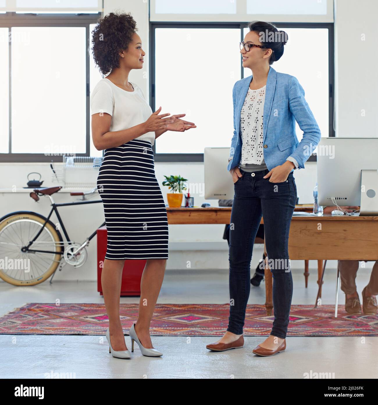 Making time for a friendly catch up at work. Shot of two colleagues ...
