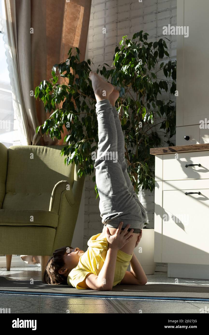Little boy practicing yoga, stretching, fitness at home. Distant online ...