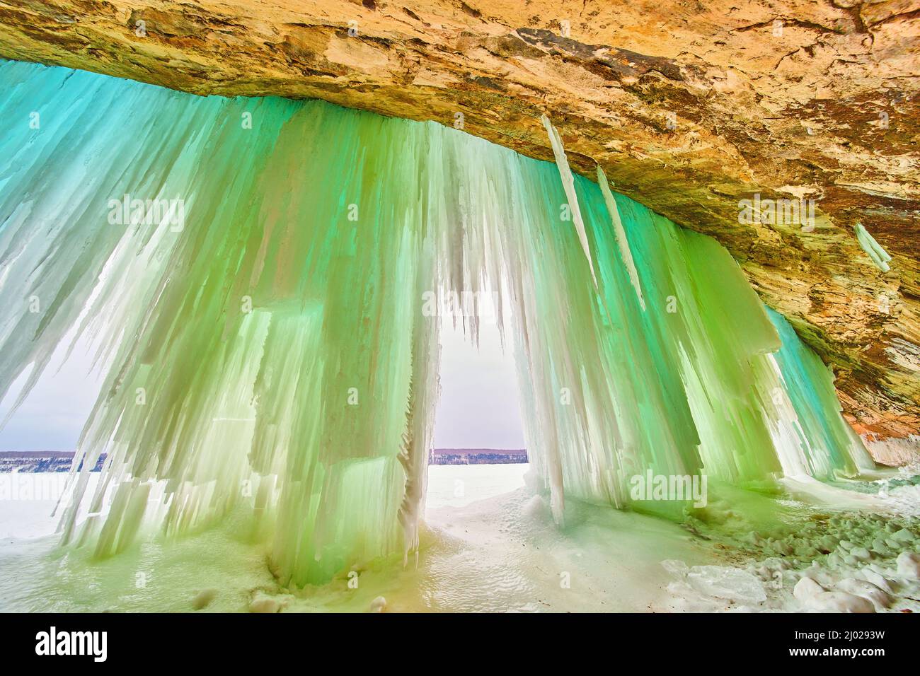 Winter ice cavern with tall sheets and icicles of blue and green ice ...