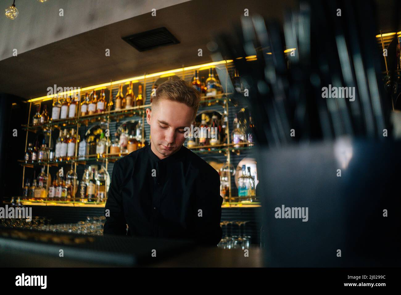 Low-angle view of confident bartender male making cocktail standing ...