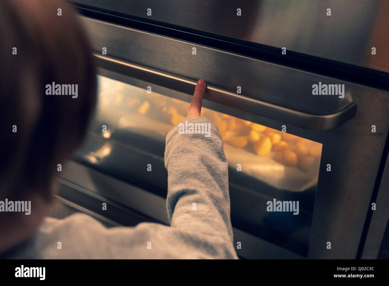 Kid touching the hot oven Stock Photo - Alamy