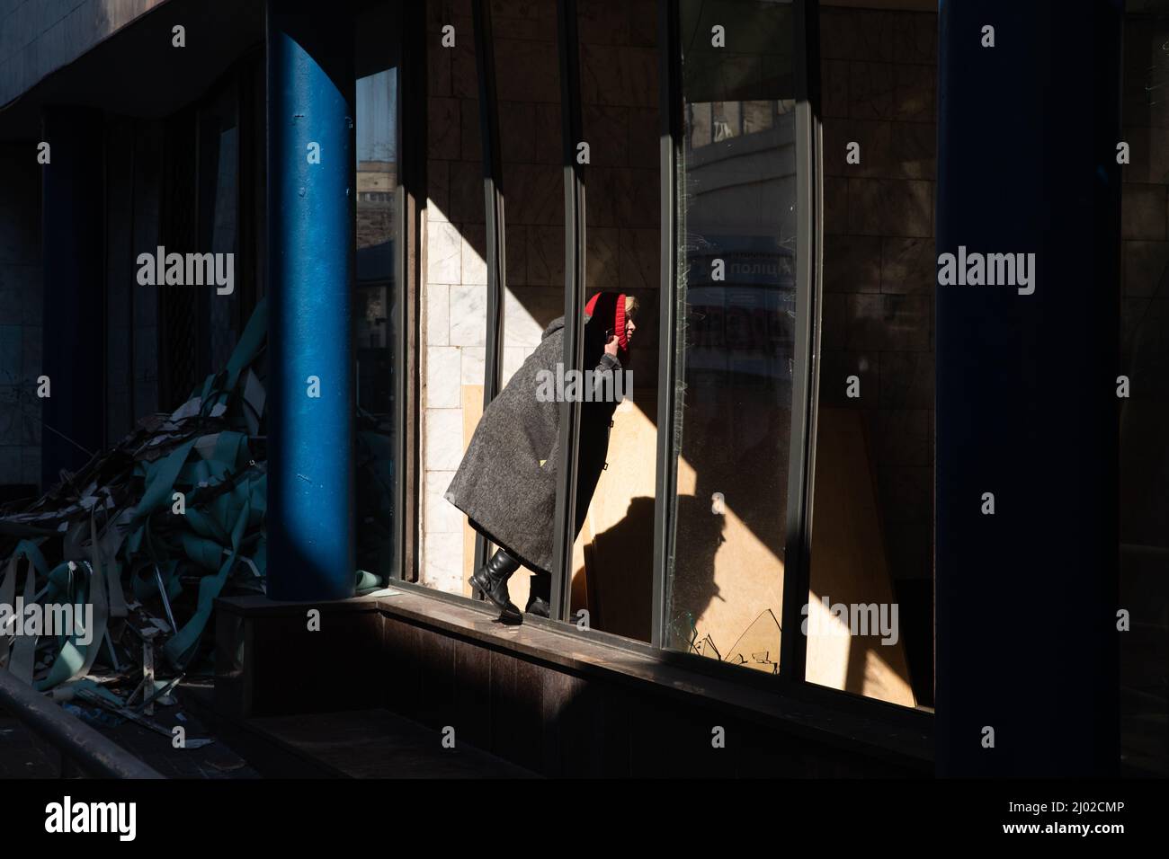 A woman peeks inside a building from a broken glass window following a ...