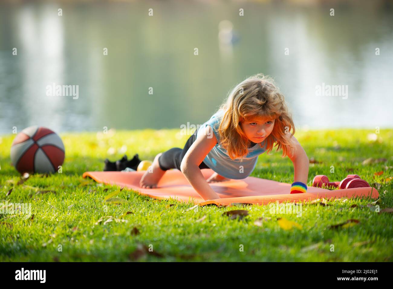 Strong kid push up exercise on the roll mat in the park outdoor ...