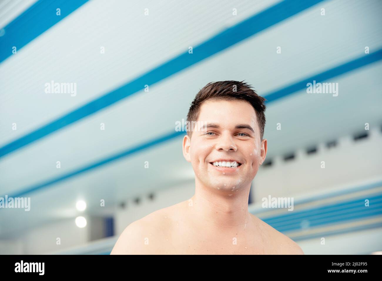 Portrait young man smiling on background of pool, concept of swimmer ...