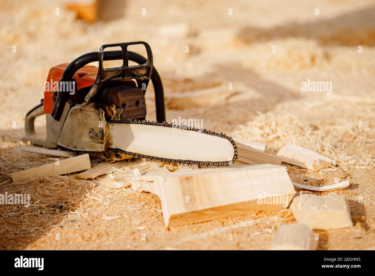 Chainsaw at construction site of wooden houses made of logs lies on ...