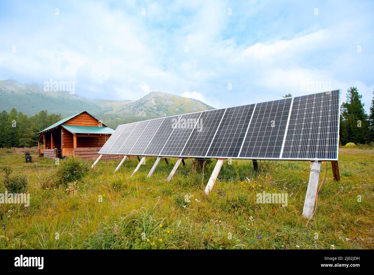Scandinavian country cottage with solar panels surrounded by mountains ...