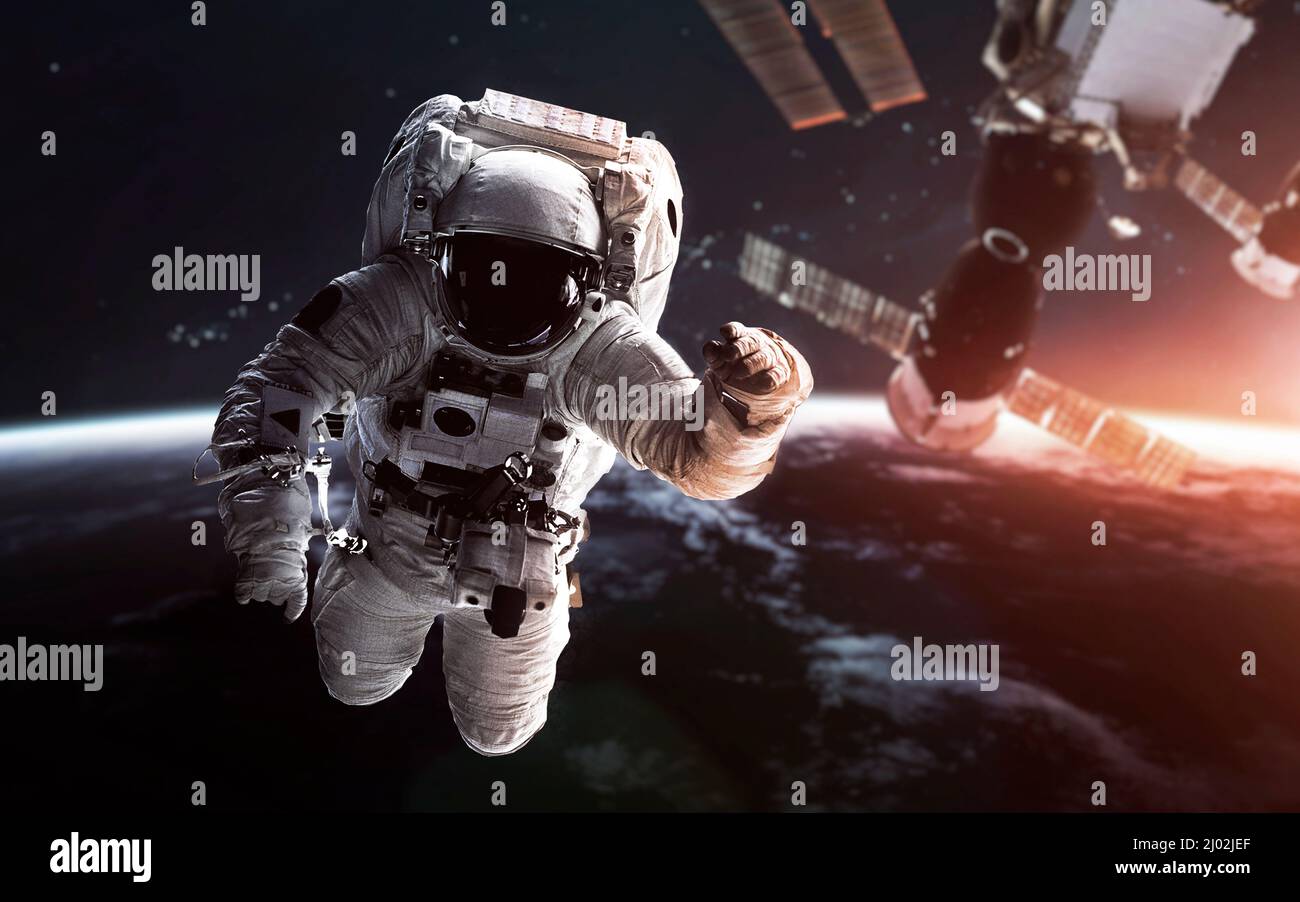 Astronaut at the Earth orbit with the Space station behind. Elements of ...