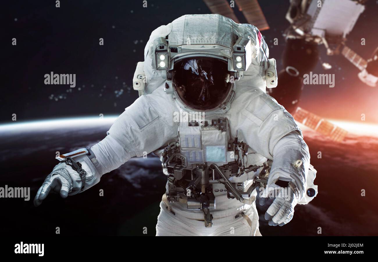 Astronaut at the Earth orbit with the Space station behind. Elements of ...