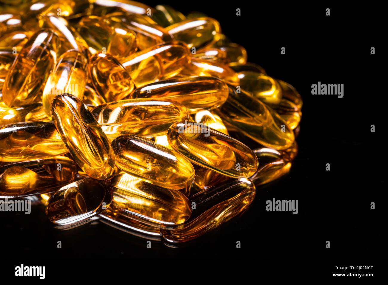 Macro Close up of Omega 3 gel capsule on a reflective black background ...