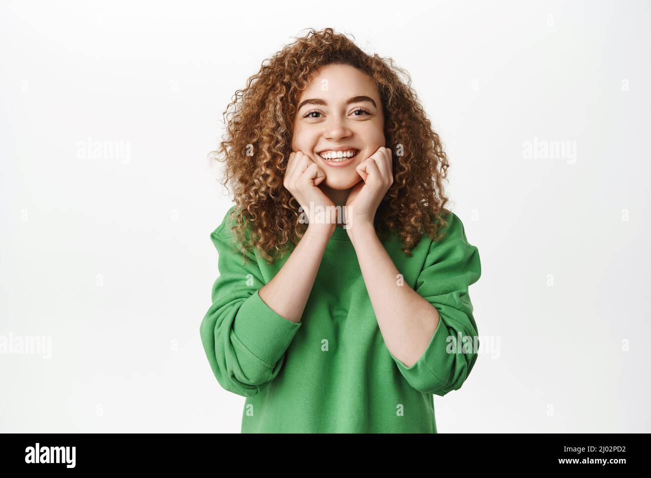 Cute smiling curly woman looking with delight and happiness, gazing ...