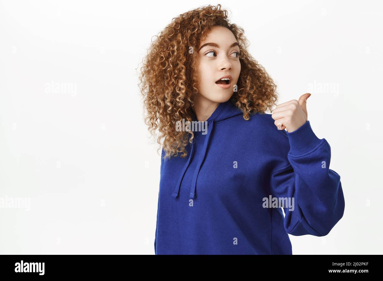 Portrait of young woman pointing finger right, showing advertisement ...
