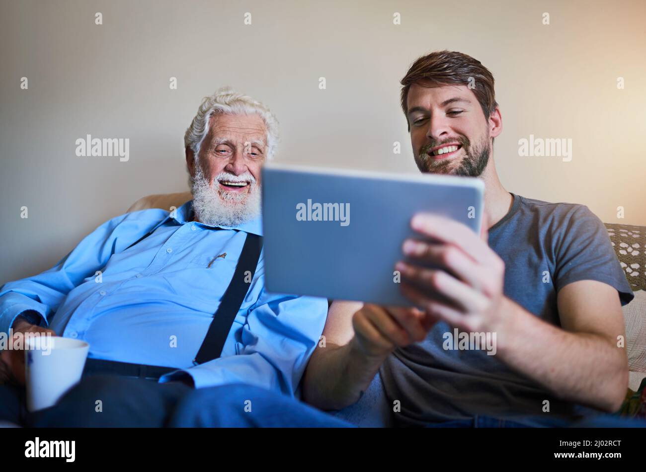 Welcoming grandpa to the age of technology. Shot of a young man showing ...