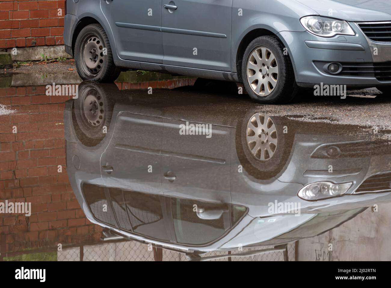 puddle on the sidewalk with a reflection of a parked car, close-up ...