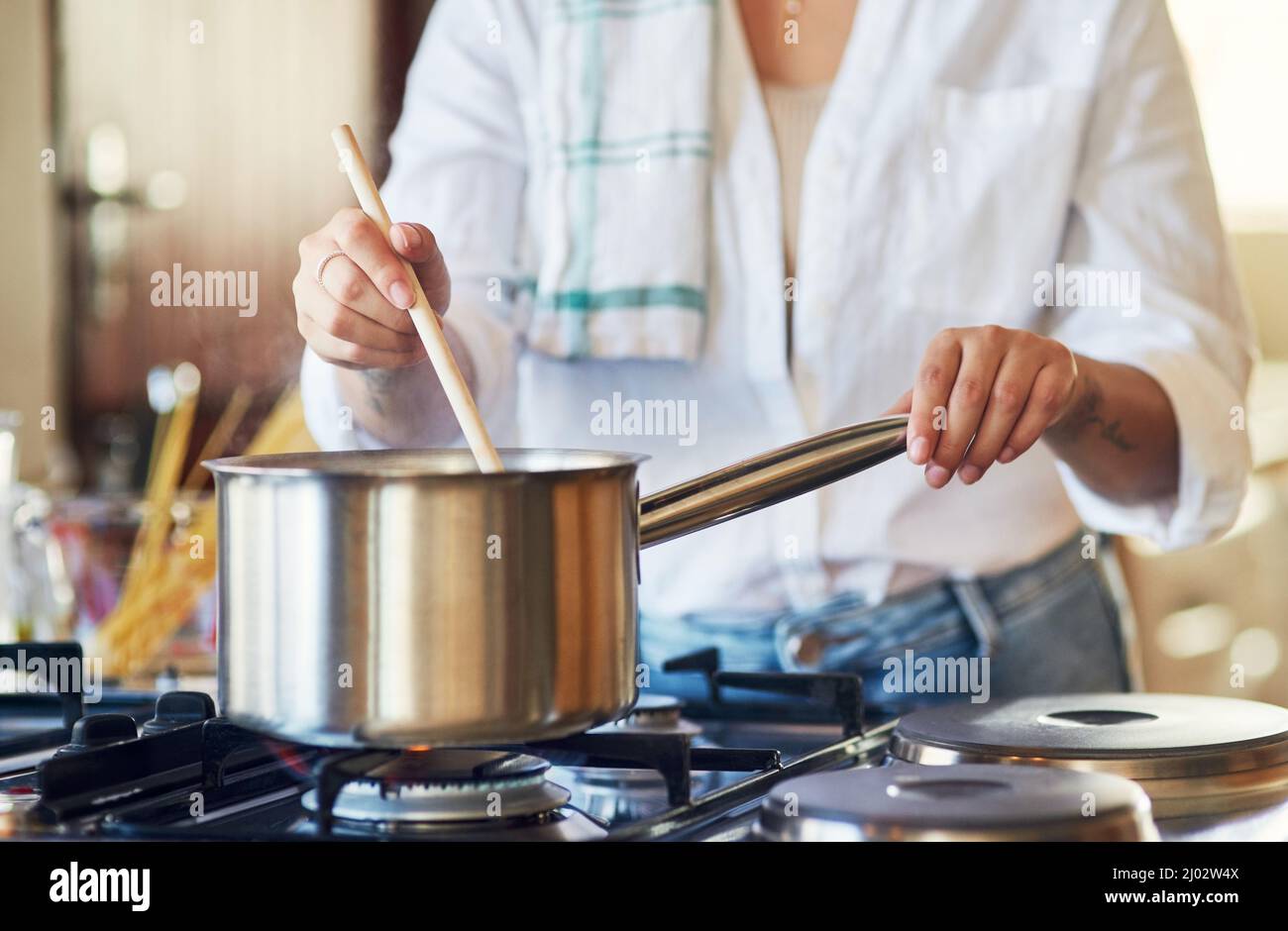 Dinner is almost ready. Cropped shot of a young woman stirring a pot in ...