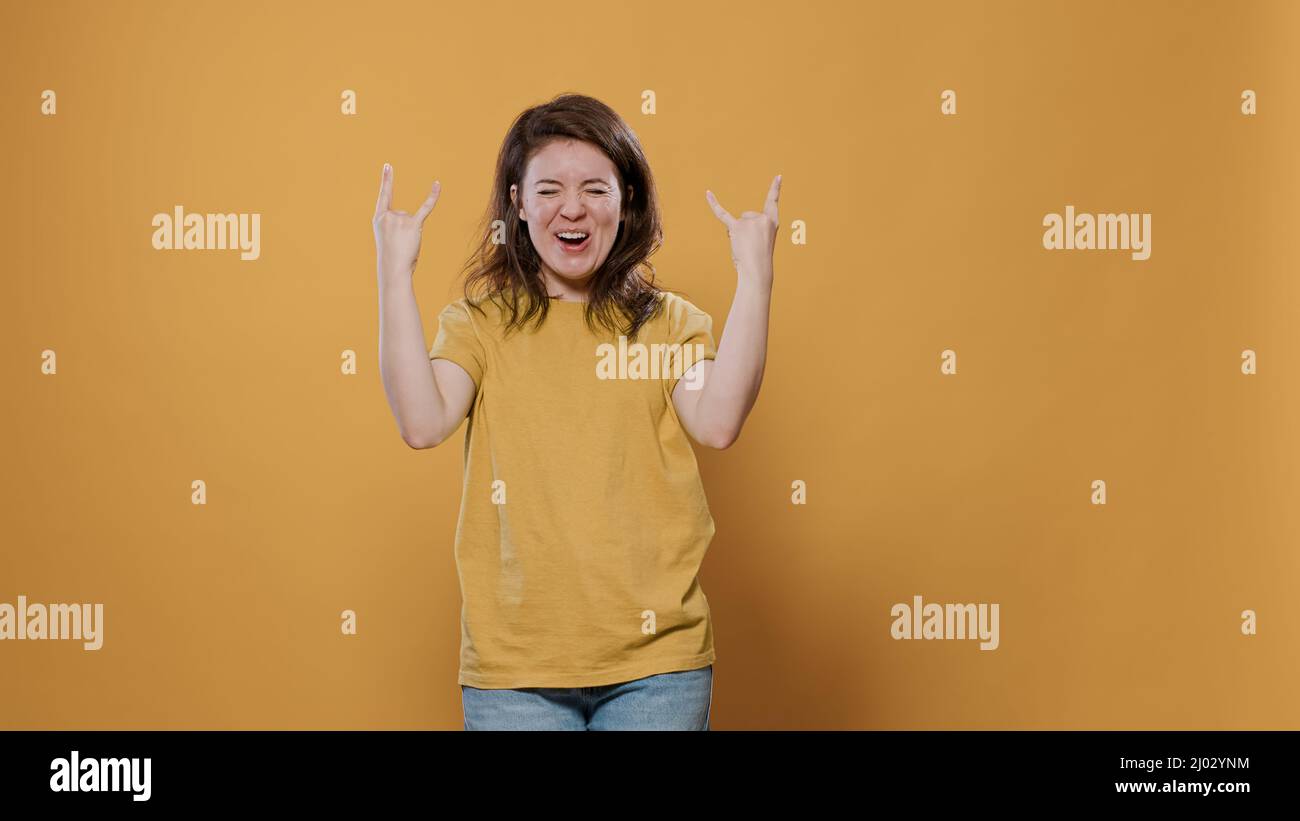 Rebel woman with positive attitude doing rock and roll hand gesture ...