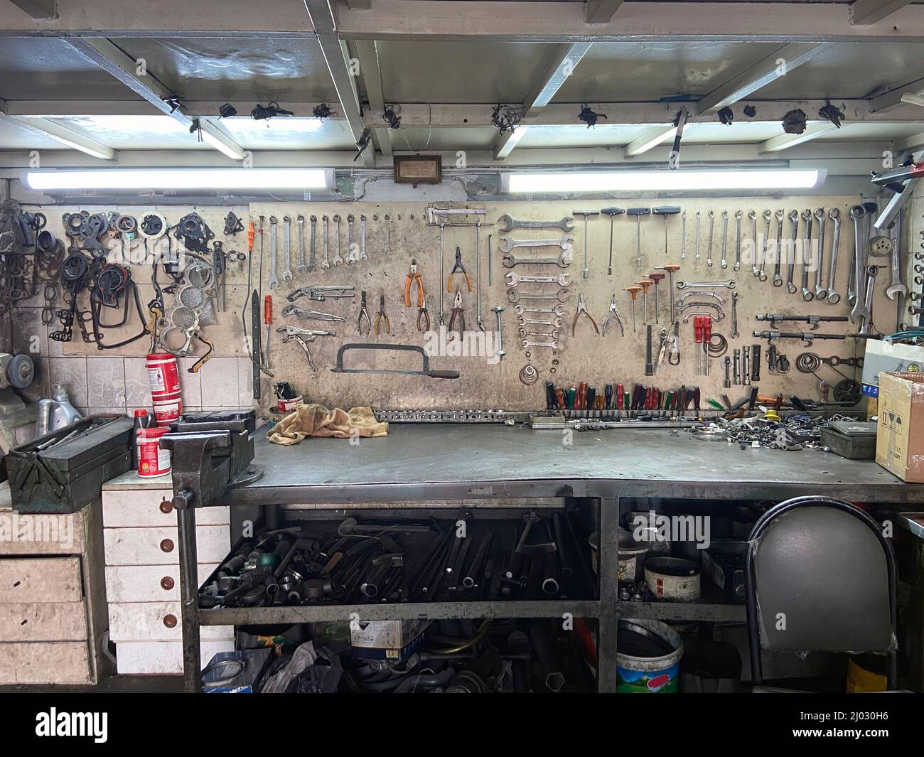 Wall of a mechanical studio with lots of tools and gears hanged on the ...