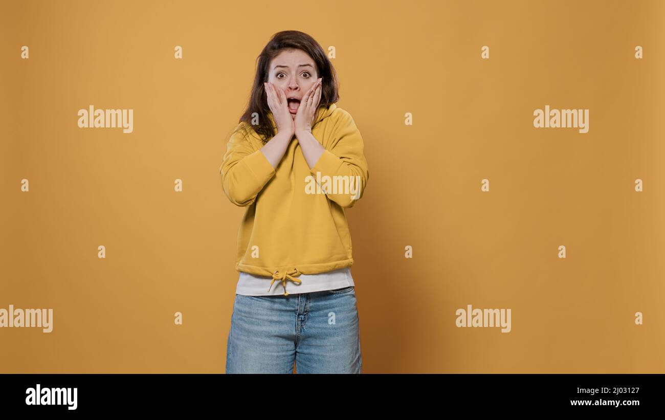 Portrait of woman being scared doing hand gesture touching face in fear ...