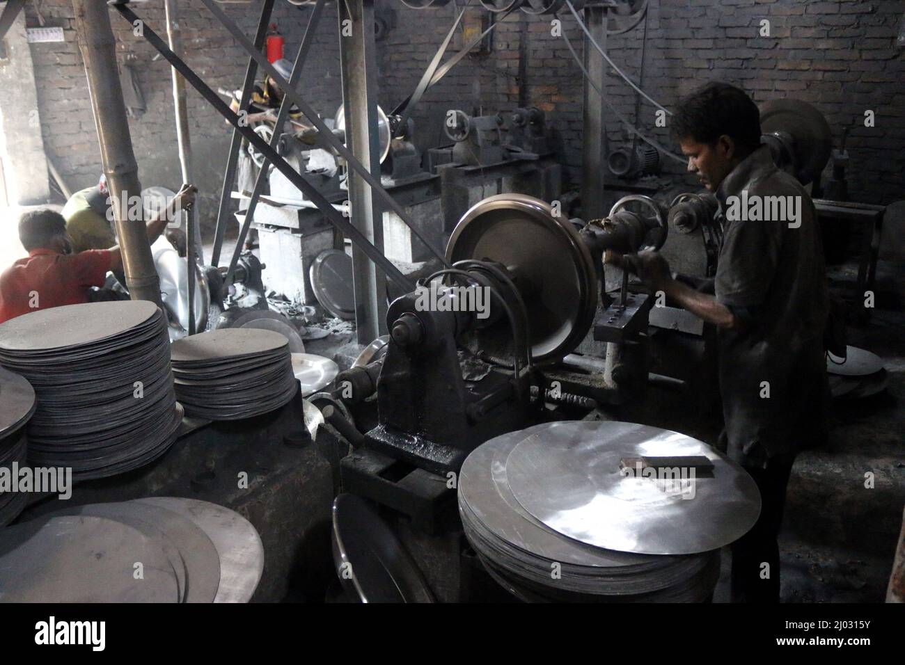 Worker works in dust environment inside in a utensil factory while ...