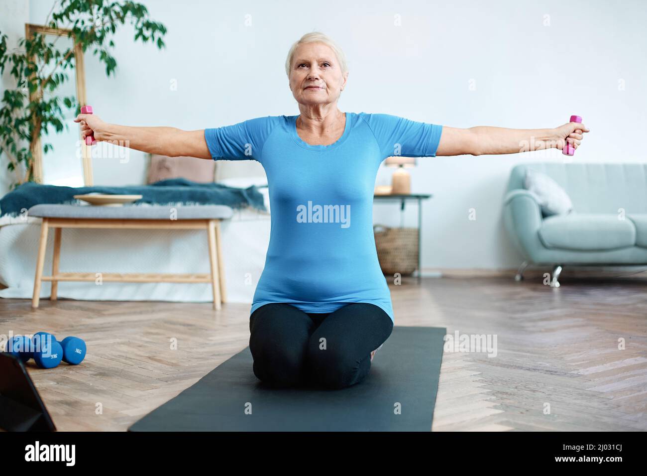 elderly woman doing an exercise with dumbbells with an online trainer ...