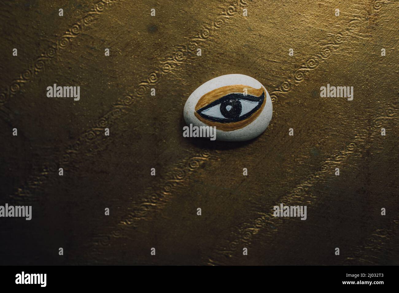 hand painted white, gold, black evil eye rock in the middle of gold ...