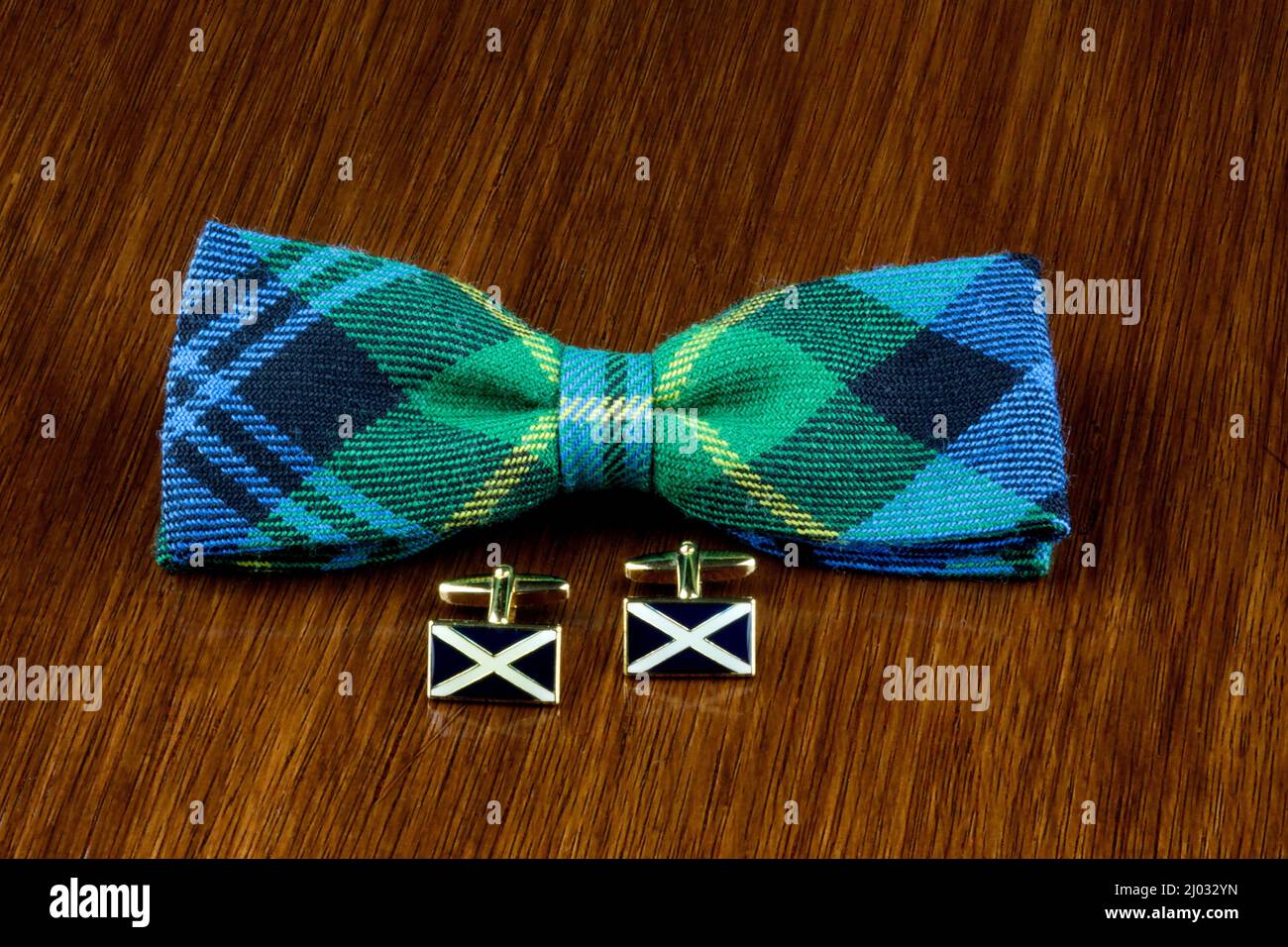 Scottish Saltire cuff links with tartan bow tie on a polished wooden ...