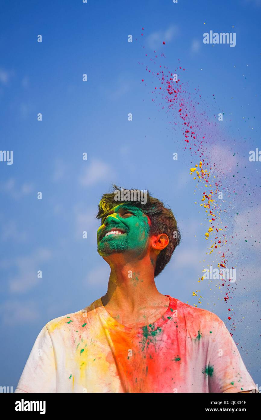Vertical portrait of a young Indian male covered in yellow and green ...