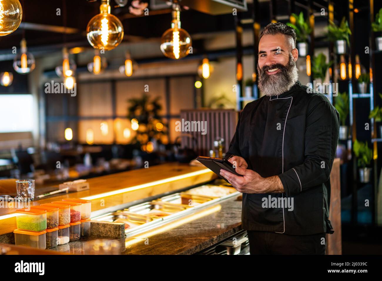 Portrait of sushi chef at sushi restaurant. He is receiving order on ...