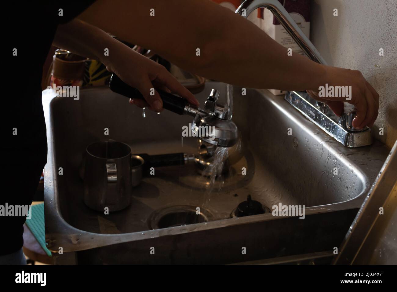 young woman's hands washing the utensils of a coffee shop in tulum ...