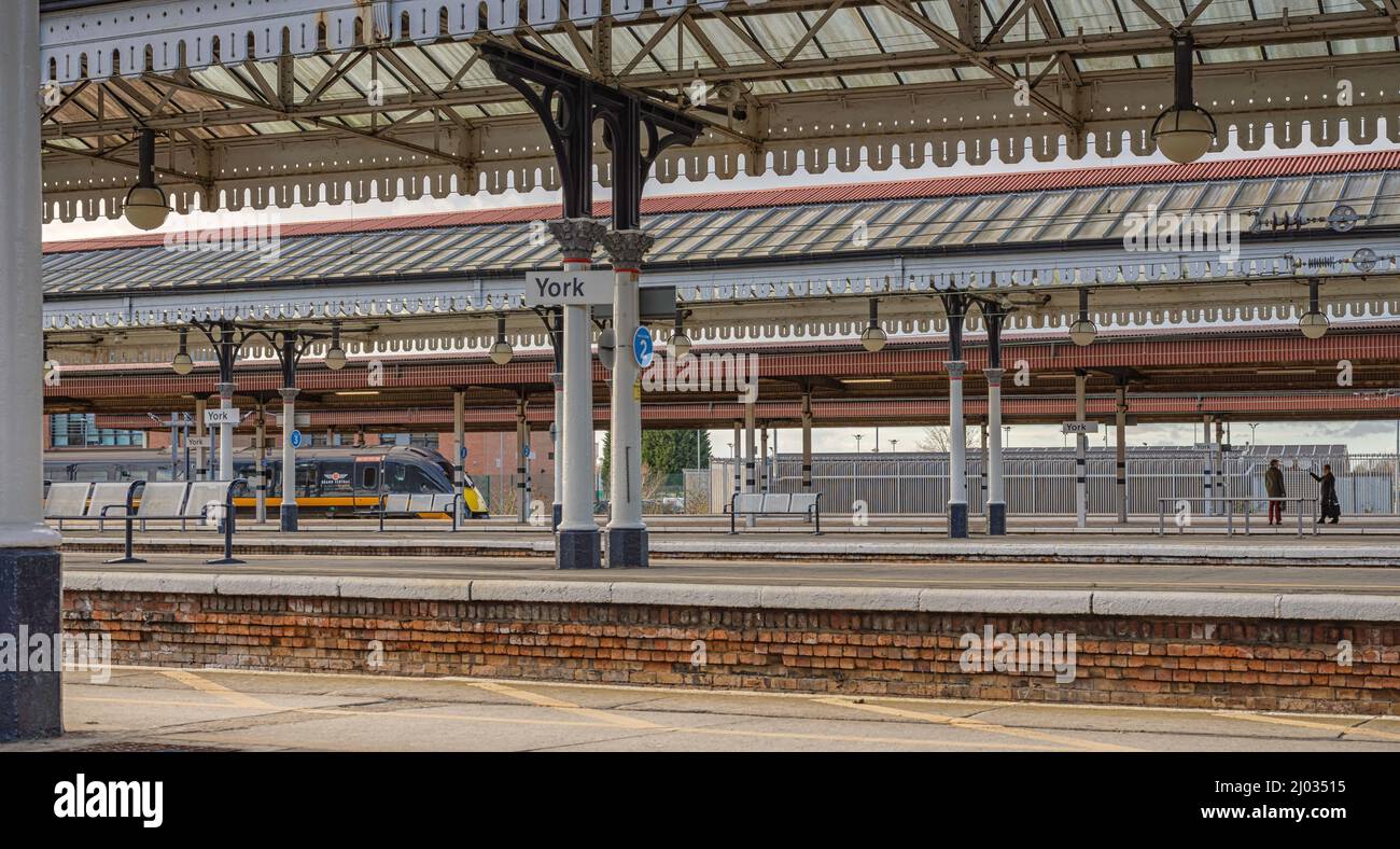 Railway station platforms with a train in the background. Overhead are ...