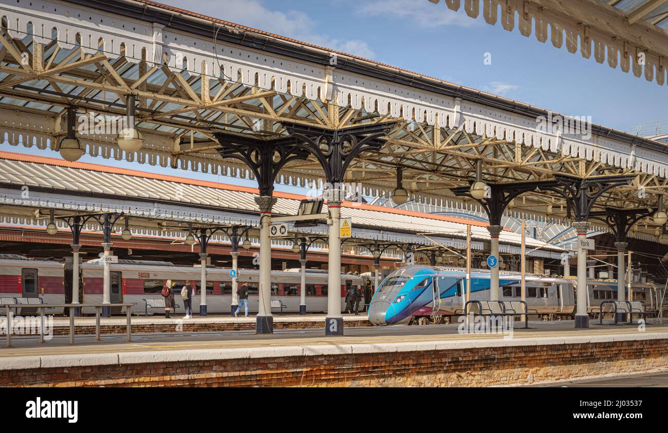 Railway station platform with a train alongside. Overhead is an ...