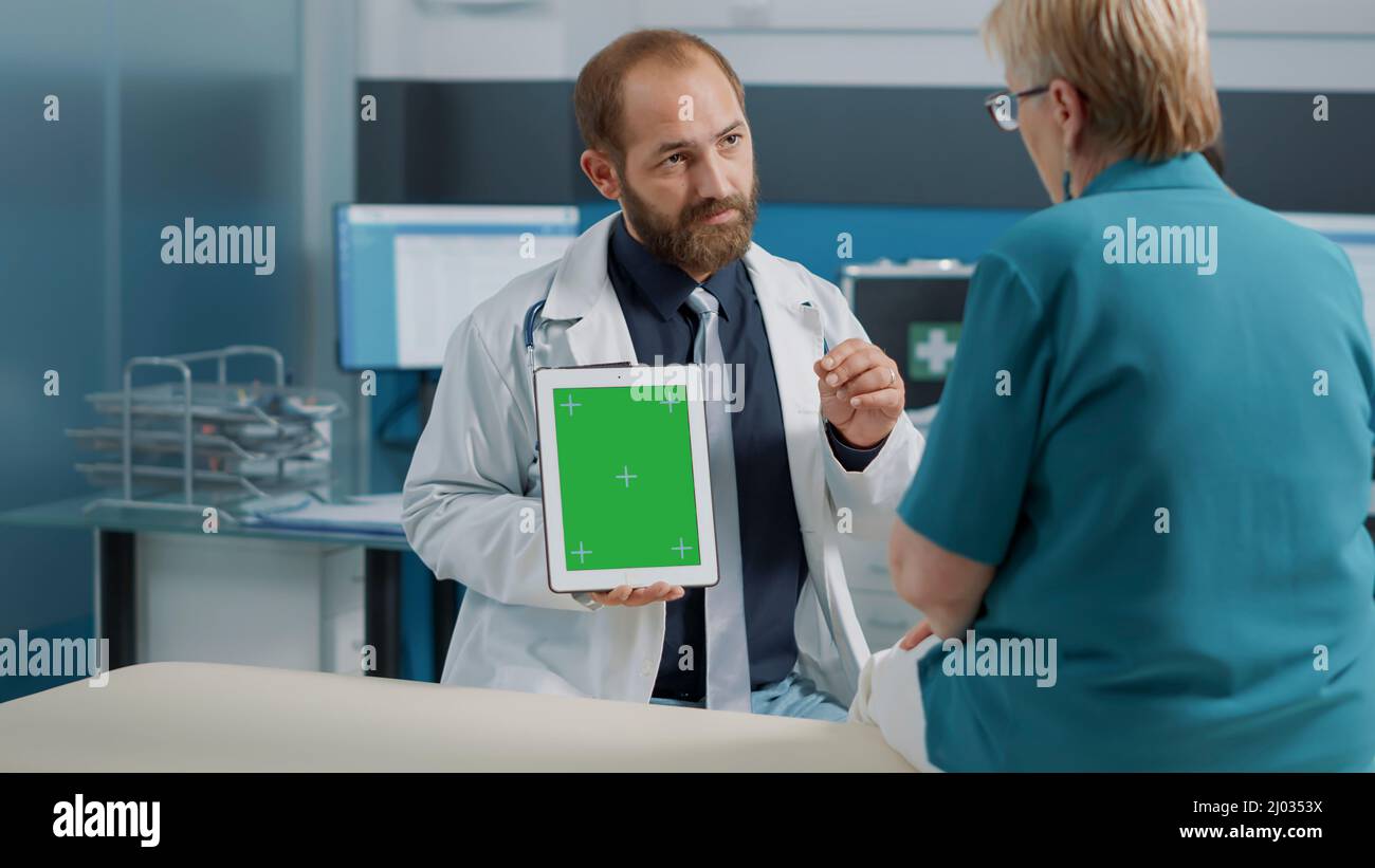 General practitioner using digital tablet with green screen at medical ...