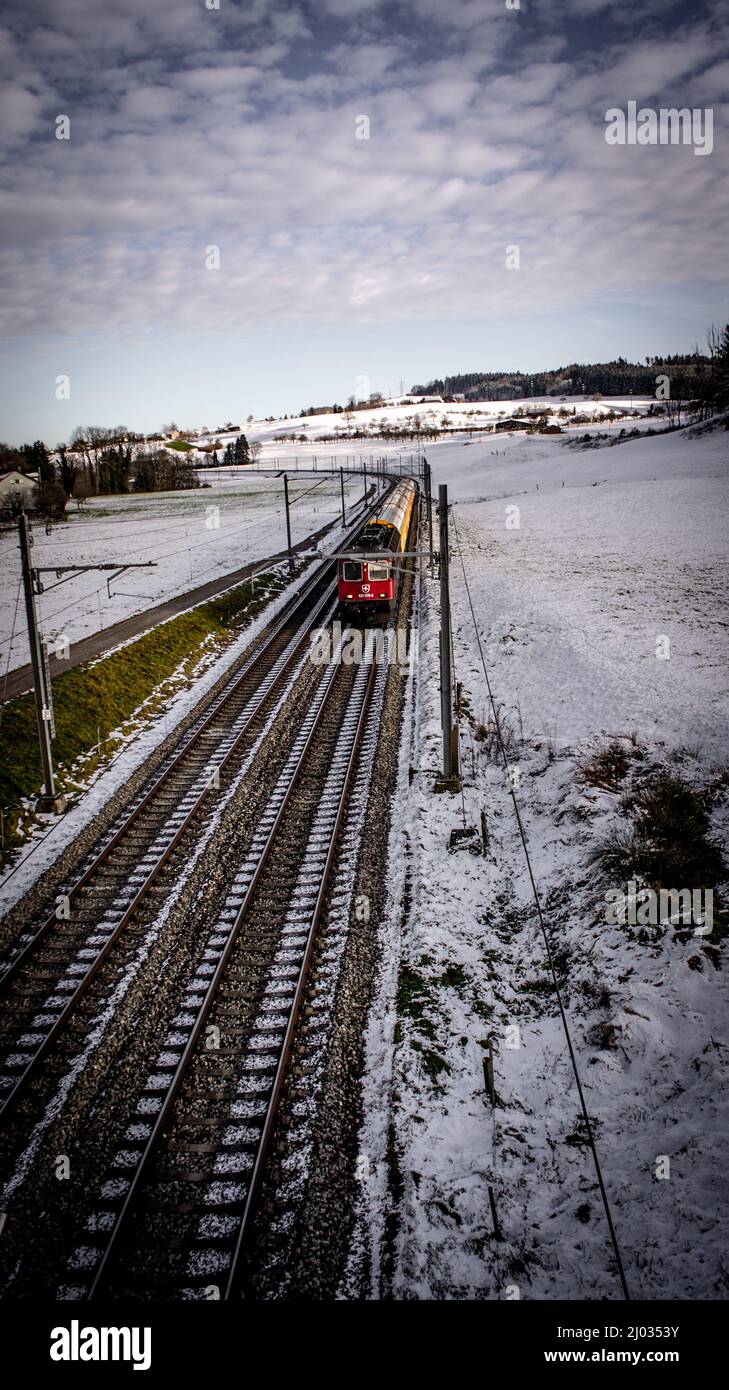 Vertical shot of a yellow train track passing through a snowy railroad ...