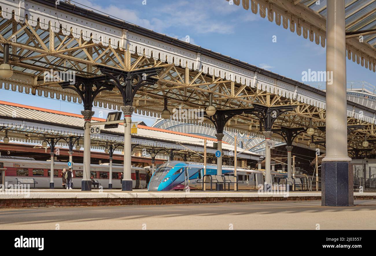 Railway station platform with a train alongside. Overhead is an ...