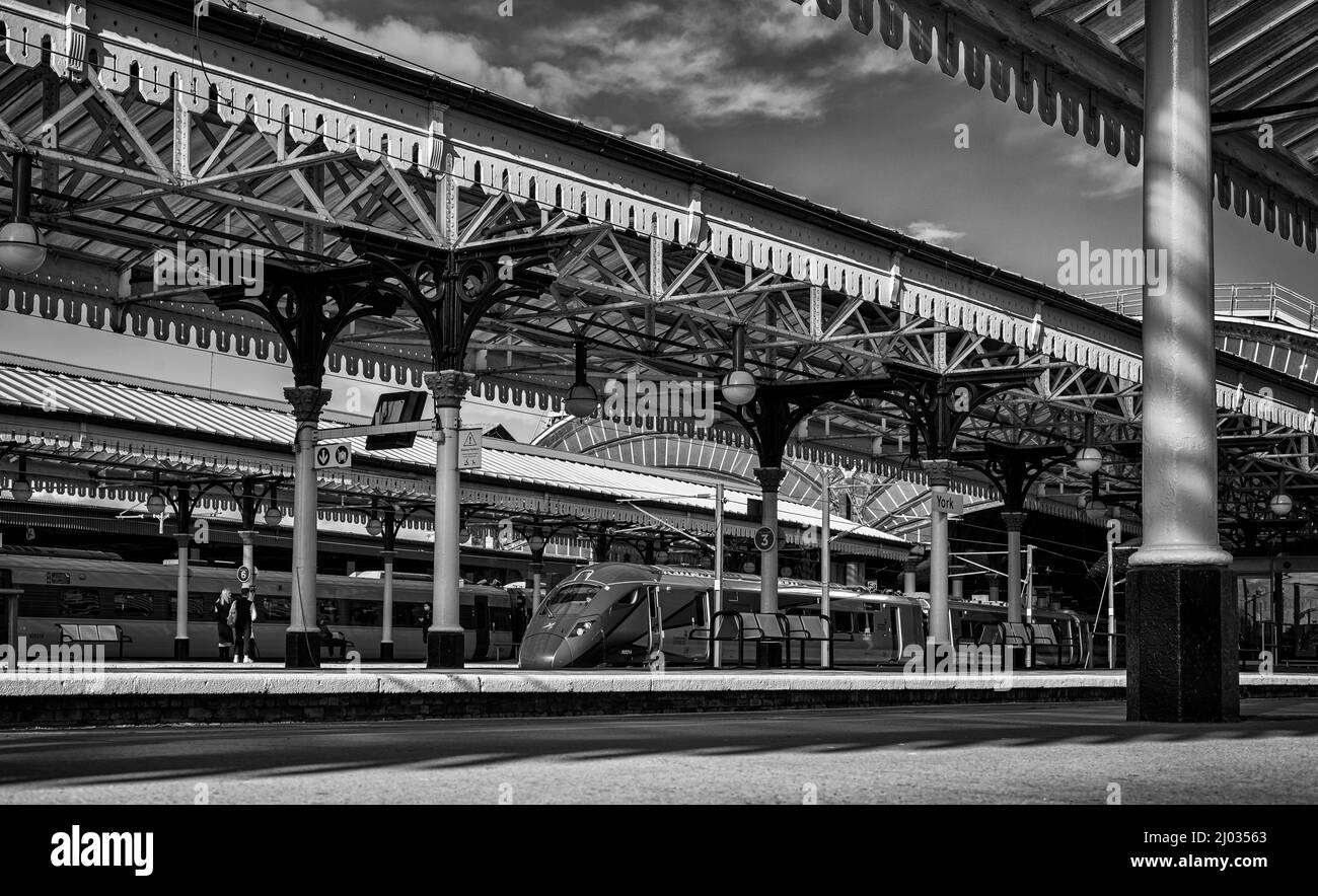 Railway station platform with a train alongside. Overhead is an ...