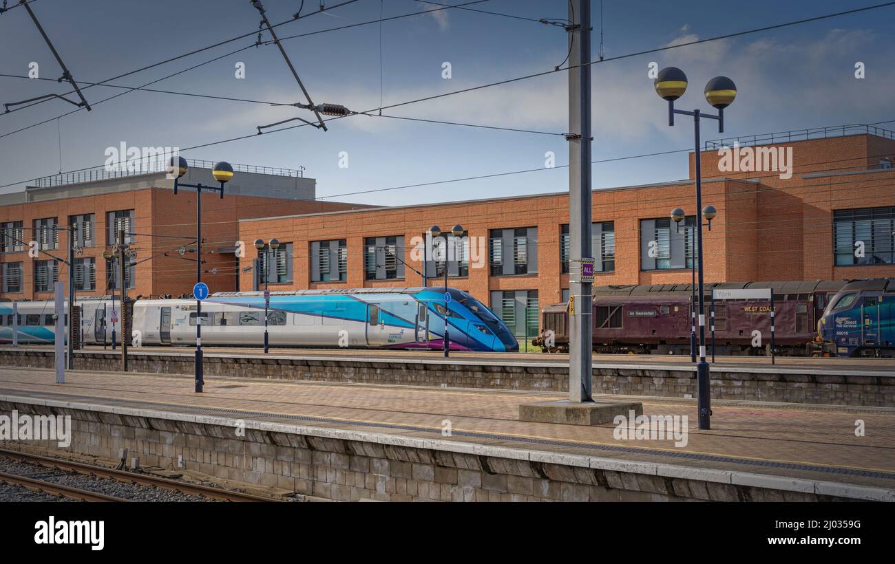 A train pulls into a railway station. Another locomotive and a building ...