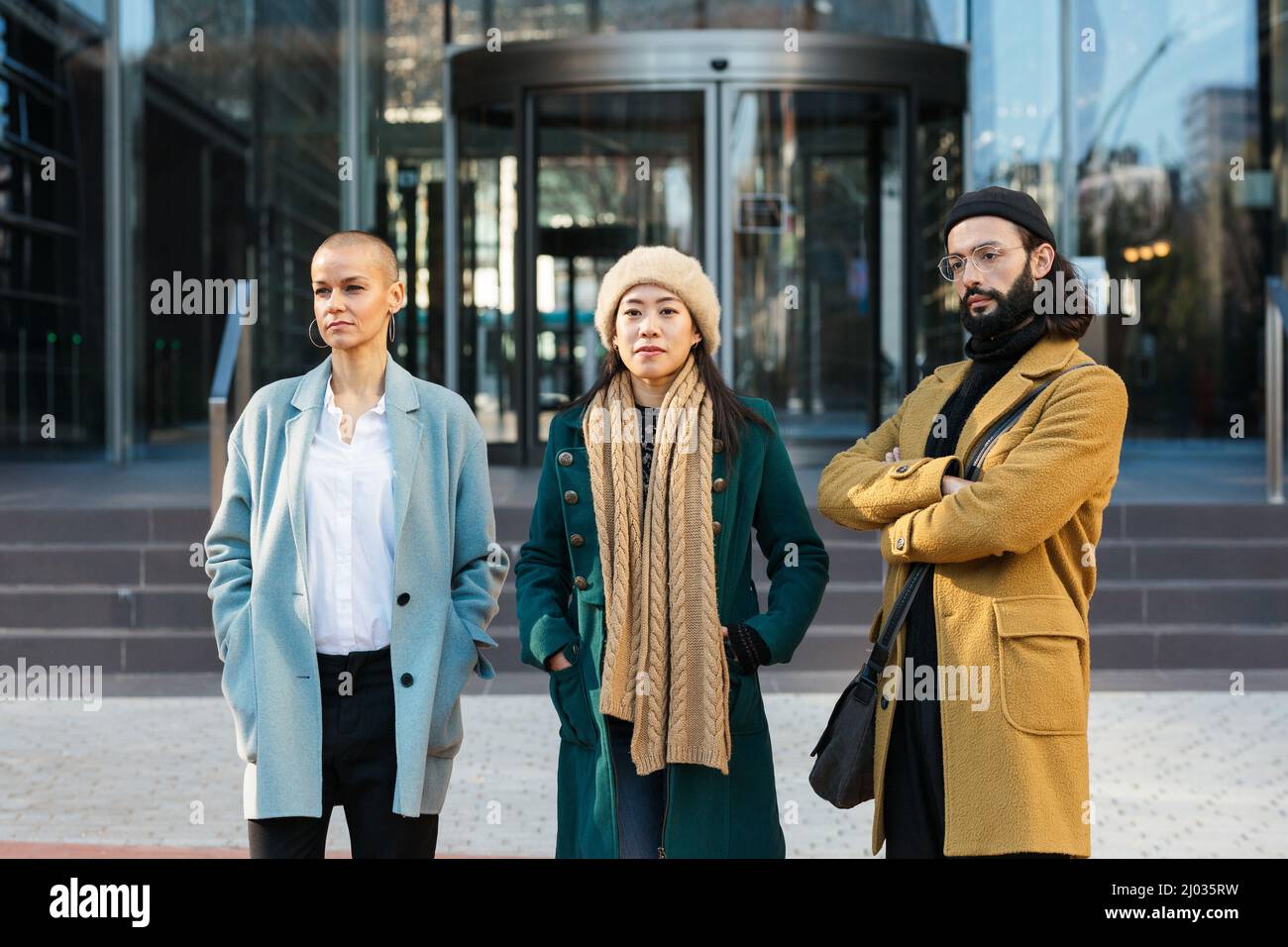Three professional business people posing together in front of the ...
