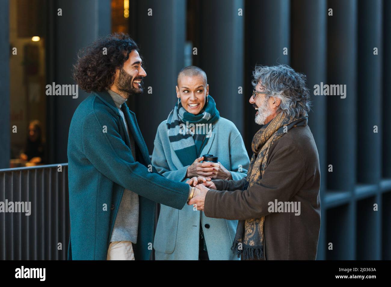 Professional business people shaking hands while talking outdoors on ...