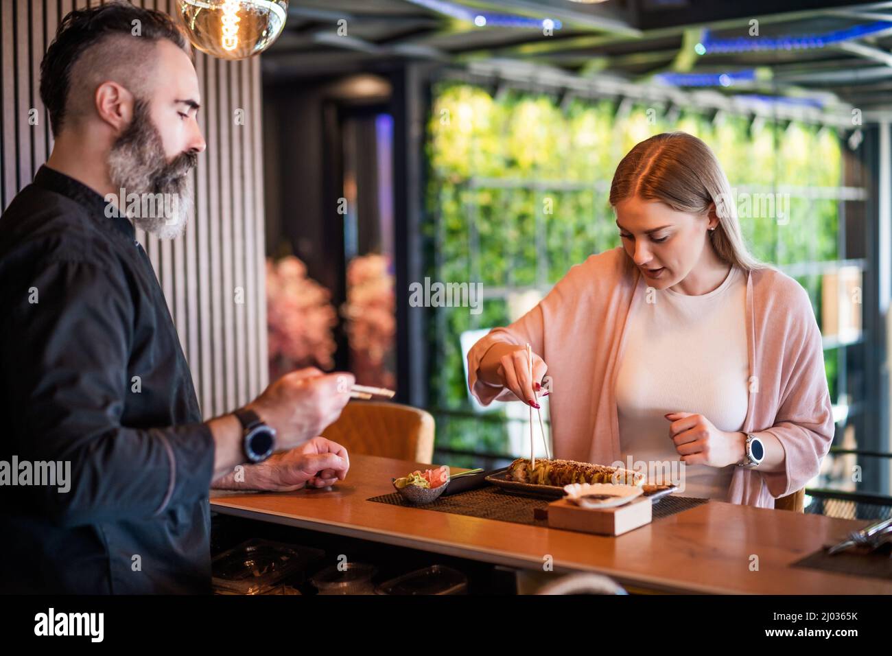Sushi master is teaching young woman how to use chopsticks at sushi ... Sushi master is teaching young woman how to use chopsticks at sushi ...