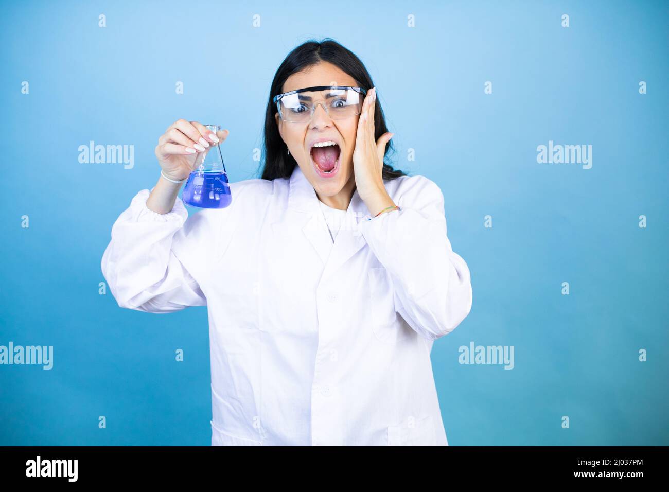 Young brunette woman wearing scientist uniform holding test tube over ...