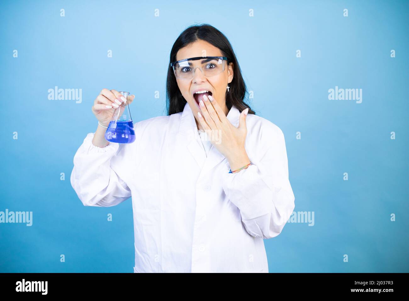 Young brunette woman wearing scientist uniform holding test tube over ...